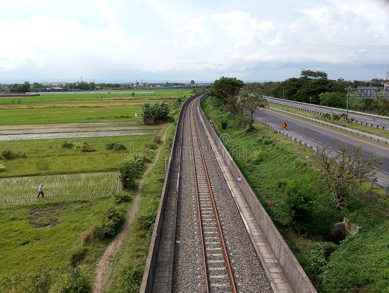 Railway Tracks Run between Vast Rice Fields and a Highway Under a ...