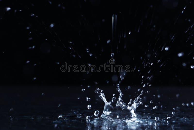 Rain Drop Falling Down into Puddle on Dark Background Stock Photo ...