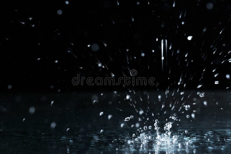 Rain Drop Falling Down into Puddle on Dark Background Stock Photo ...