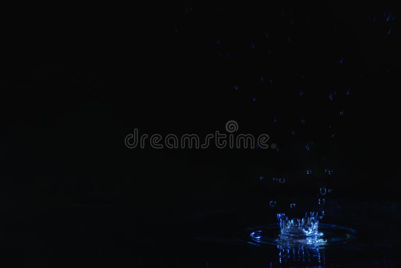 Rain Drop Falling Down into Puddle on Dark Background Stock Photo ...