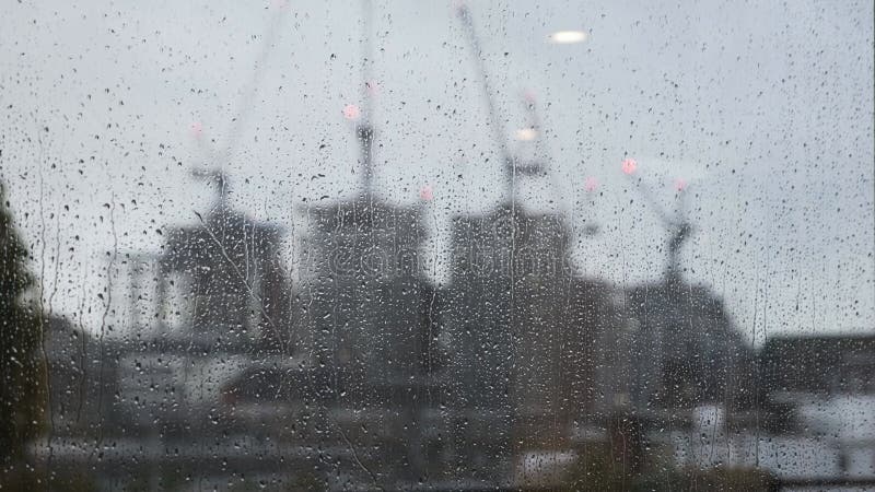 Rain Falling Down on Window with Blurred Construction Cranes in ...
