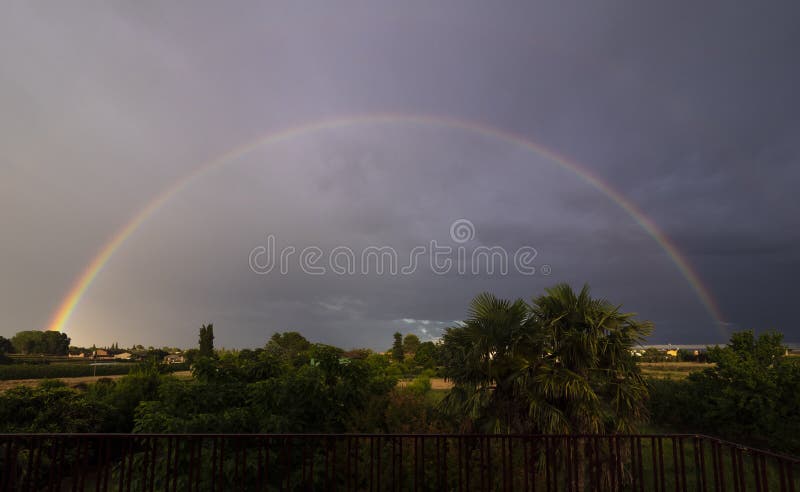 Rainbow with Dark Clouds and Sun Rays Stock Photo - Image of beautiful ...