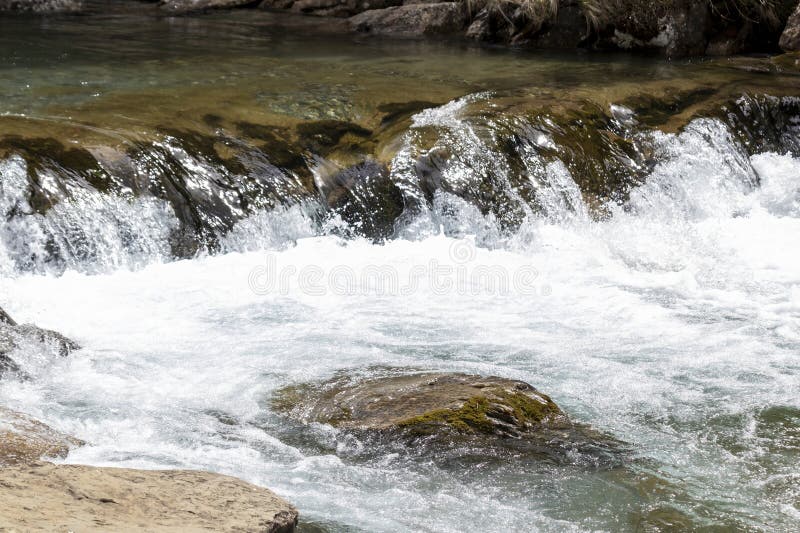 A Rapid, Clear River Flowing Over Smooth, Moss-covered Rocks in a ...