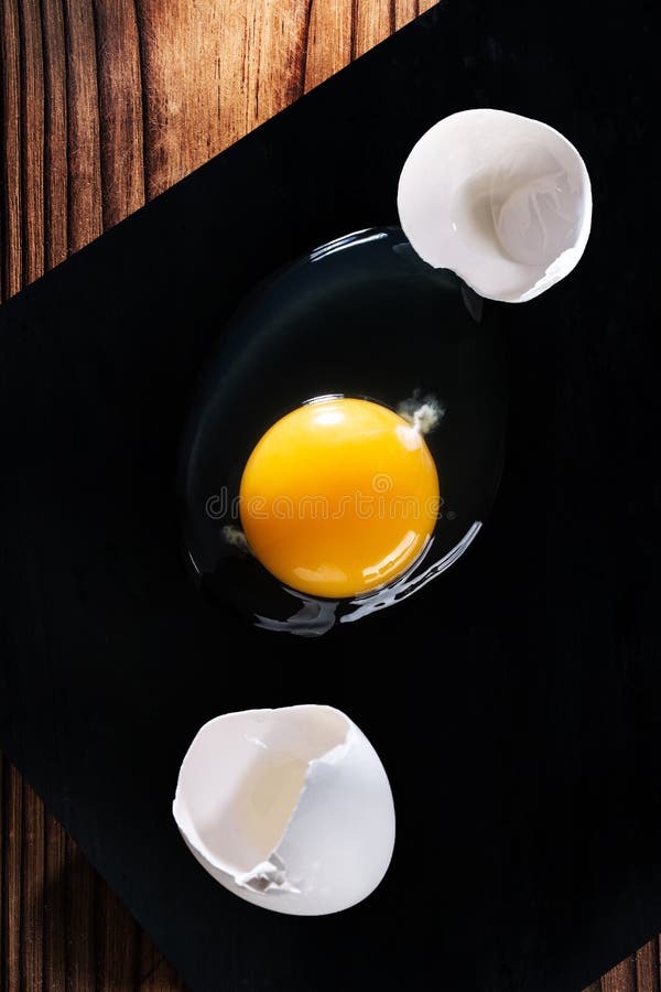 Raw Broken Egg and Shell on Black Cutting Board on Wooden Table Stock ...