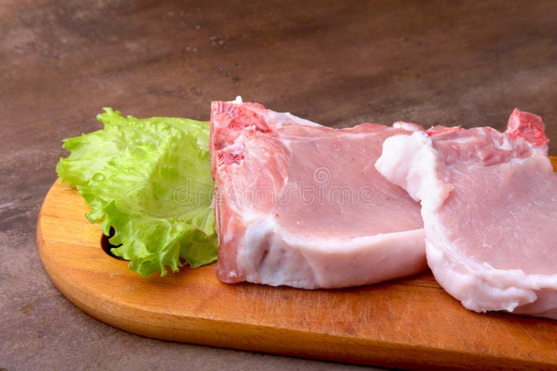 Raw Chop on a Rustic Cutting Board with Salt, Pepper and Grinder for ...