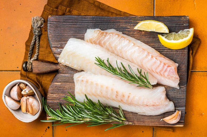 Raw Cod Fish Fillets, Codfish with Rosemary on Wooden Board. Orange ...