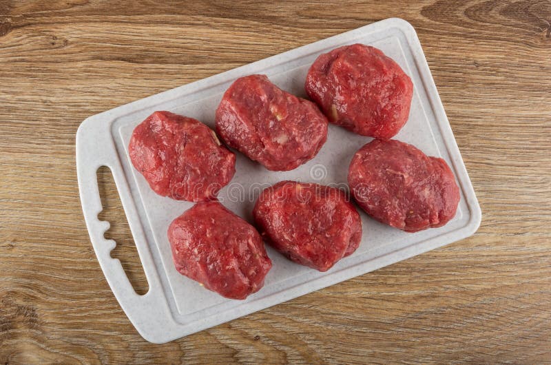 Raw Cutlets on Plastic Cutting Board on Wooden Table. Top View Stock ...