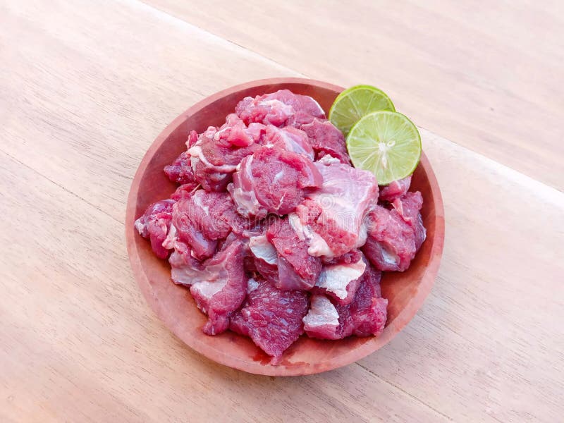 Raw Goat Meat Served with Lime on a Wooden Plate on a Wooden Background ...