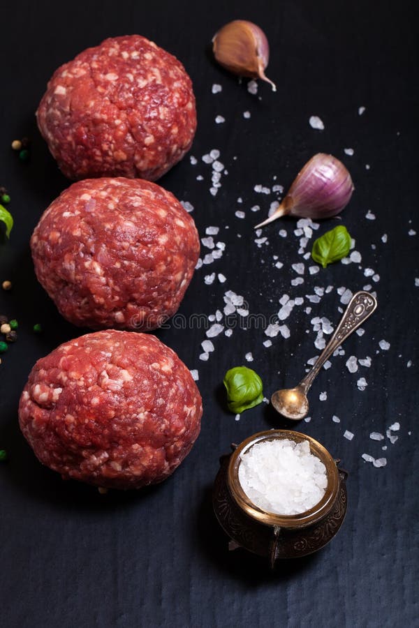 Raw Ground Beef Meat Steak Cutlets with Herbs and Spices on Black Table ...