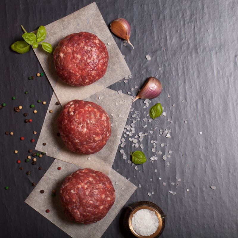 Raw Ground Beef Meat Steak Cutlets with Herbs and Spices on Black Table ...