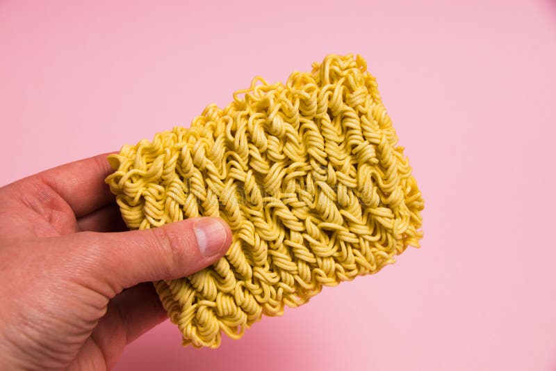 Raw Instant Noodles in Hand on Pink Background Stock Photo - Image of ...
