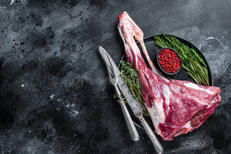 Raw Lamb Mutton Leg Meat on the Bone with Herbs. Black Background. Top ...