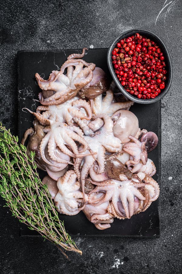 Raw Mini Baby Octopus on a Marble Board with Thyme. Black Background ...