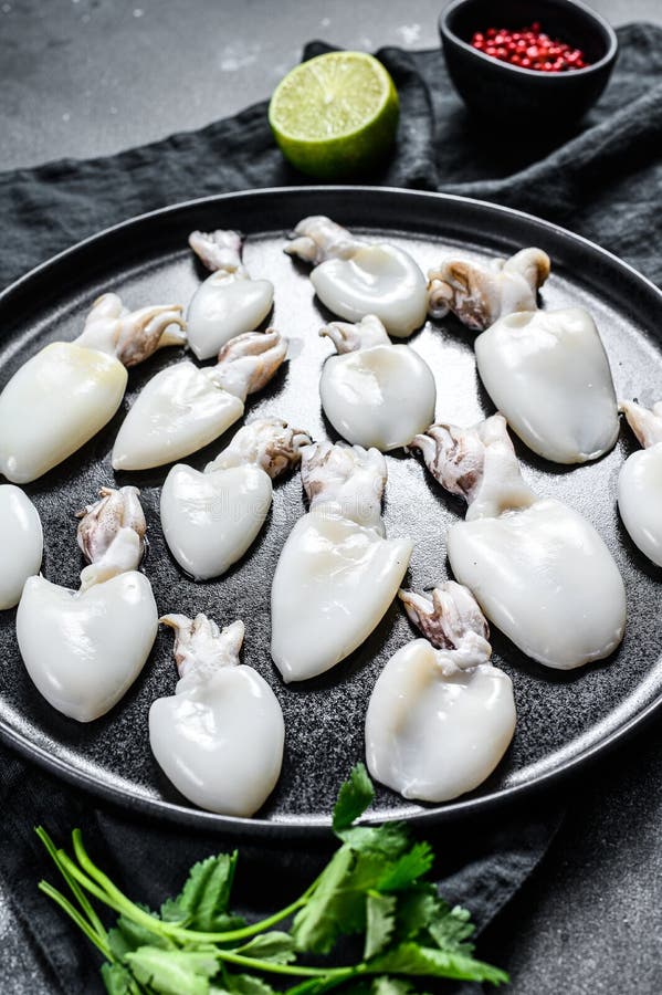 Raw Mini Cuttlefish with Rosemary and Parsley on a Plate. Black ...