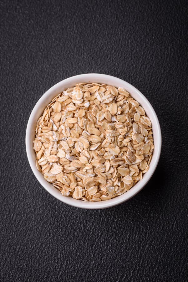 Raw Oatmeal Flakes in a Ceramic Bowl on a Dark Concrete Background ...