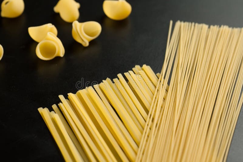 Raw Organic Macaroni Shells and Spaghetti on Black Stock Photo - Image ...