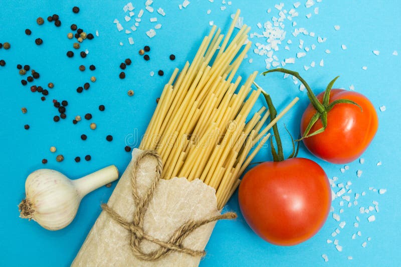 Raw Pasta on a Blue Background in a Rustic Package. Tomatoes, Garlic ...