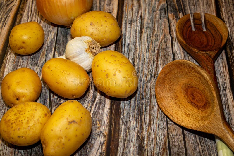 Raw Potatoes, Garlic and a Few Wooden Spoons on a Wooden Table. Stock ...