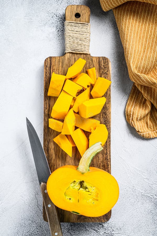 Raw Pumpkin Cubes on a Cutting Board. White Background Stock Photo ...