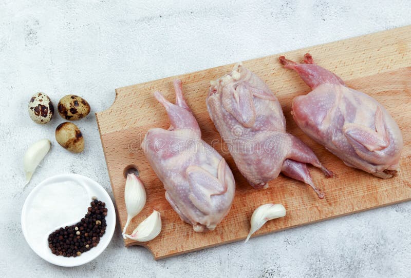 Raw Quails on a Wooden Cutting Board on a Light Gray Background Stock ...