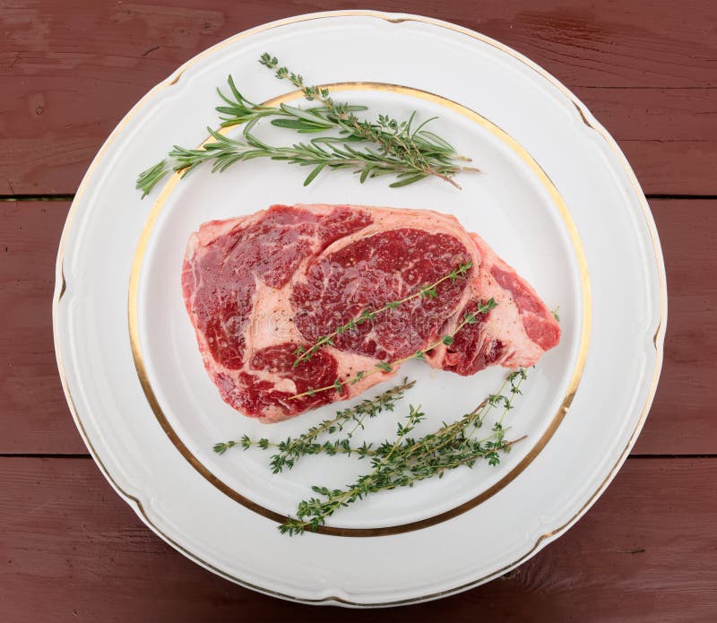 Raw Rib-eye Steak on Plate, Wooden Table Stock Photo - Image of ribeye ...