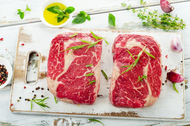Raw Rib Eye Steaks on a White Cutting Board. Stock Photo - Image of ...