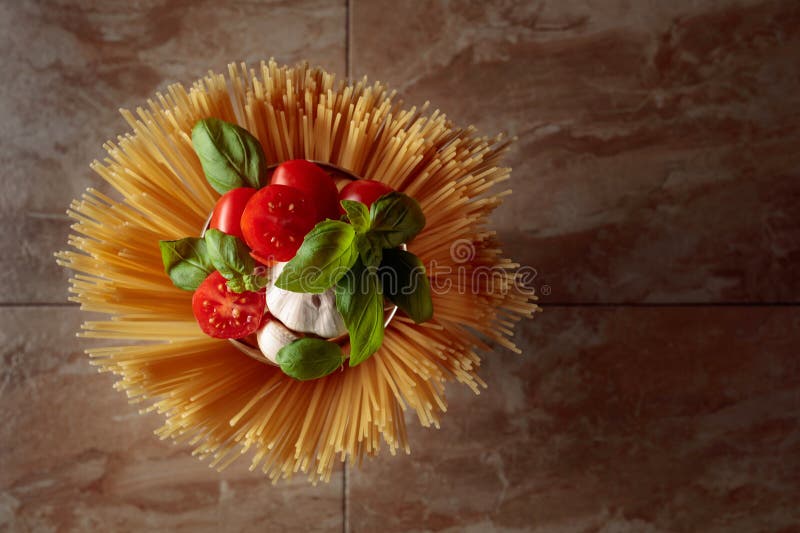 Raw Spaghetti with Tomato, Garlic, and Basil on a Brown Ceramic Table ...