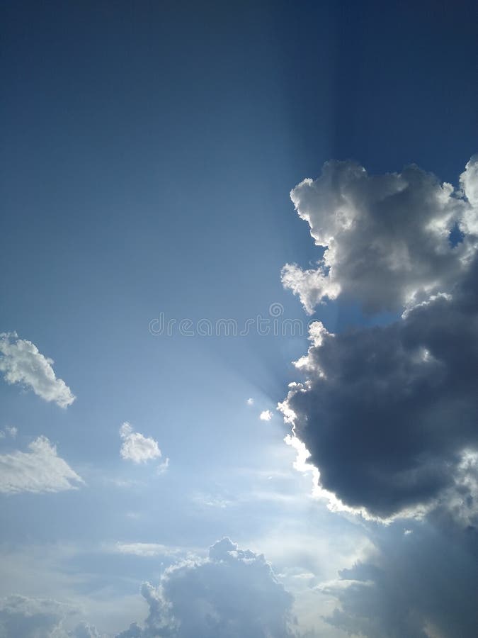 The Rays of the Sun Come Out from Behind the Clouds in the Blue Sky ...