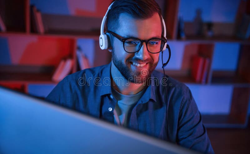Read and Blue Neon Lighting. Man is Sitting by a Computer Indoors at ...