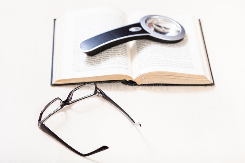 Eyeglasses and Magnifier on Open Book on Table Stock Photo - Image of ...