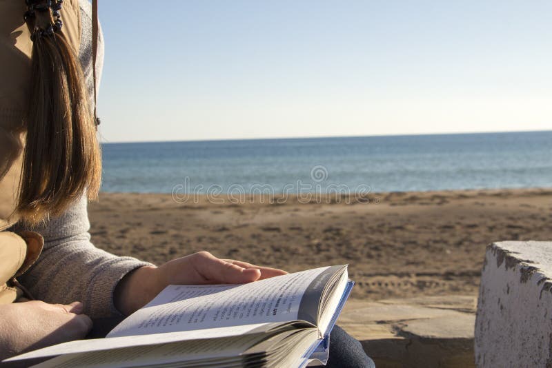 Reading book near seaside stock image. Image of book - 65179927