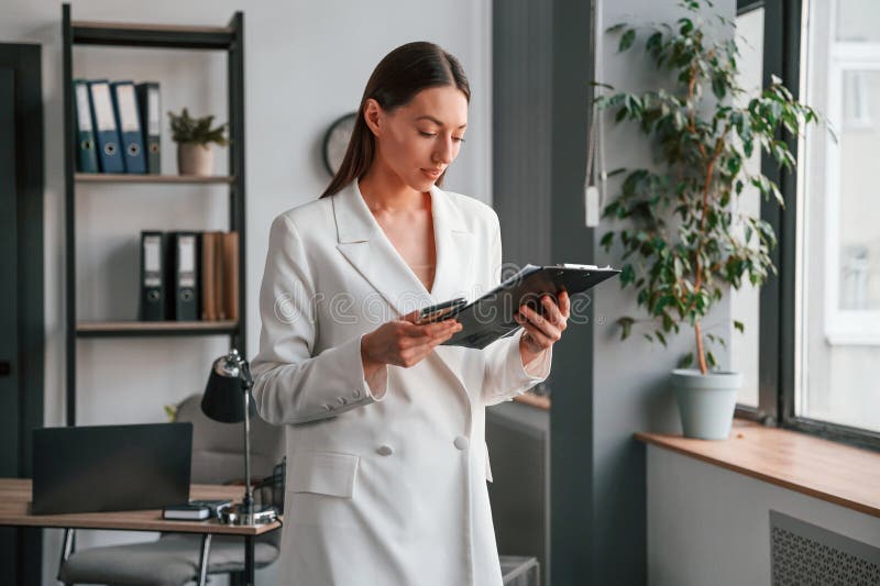 Reading Document in Notepad. Young Beautiful Woman in Formal Clothes is ...
