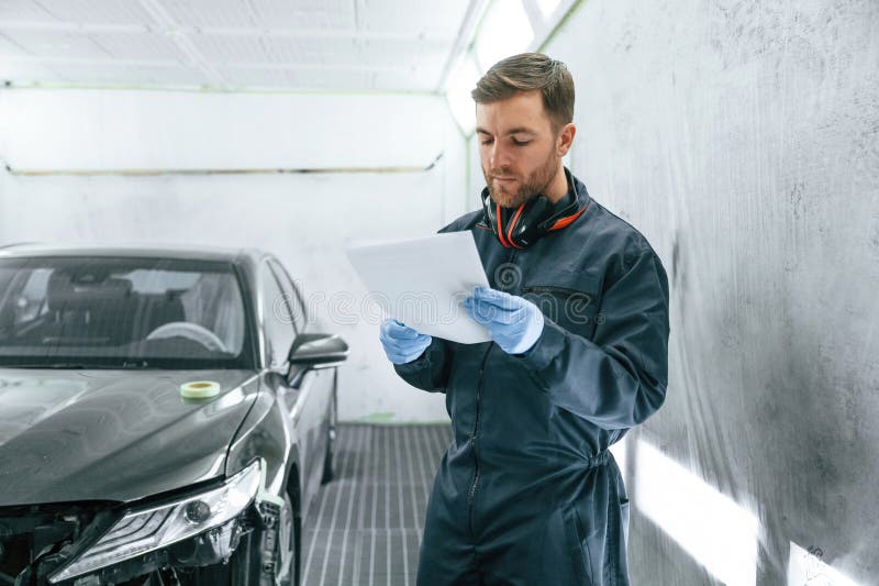 Reading Information. Car Painter is Standing in the Garage with ...