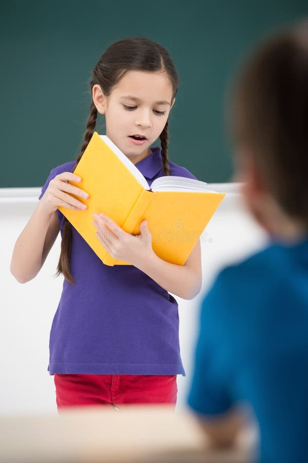 Reading To the Class. Confident Little Schoolgirl Reading a Book Stock ...