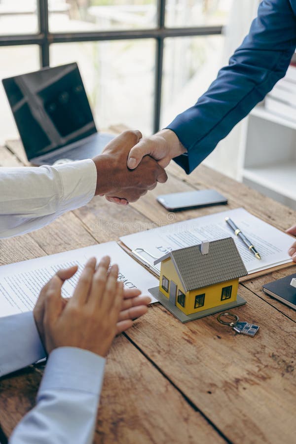 A Real Estate Agent Shakes Hands with a Client after Signing the ...