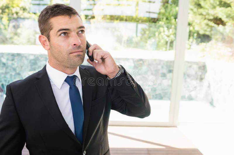 Executive Standing by Glass Wall Holding Smartphone with Sunlight ...