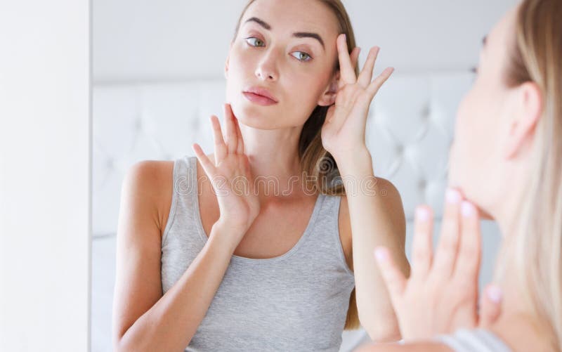 Real Young Woman Looking in a Mirror and Touching Her Face Stock Photo ...