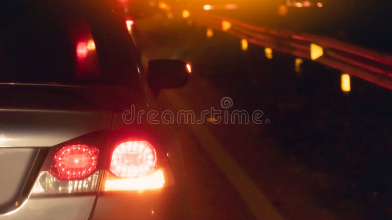 Rear of a Car at Night with Illuminated Tail Lights and a Side Mirror ...