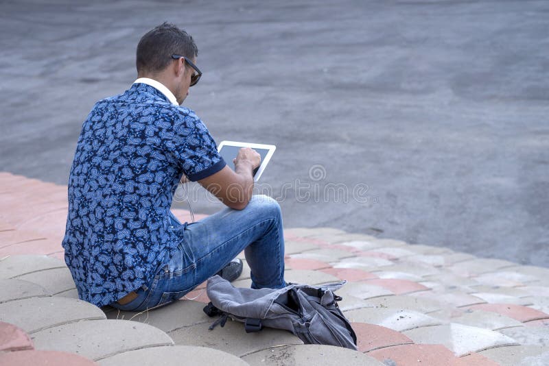 Rear Image of Young Man Sitting on Bleachers Using a Tablet Stock Photo ...