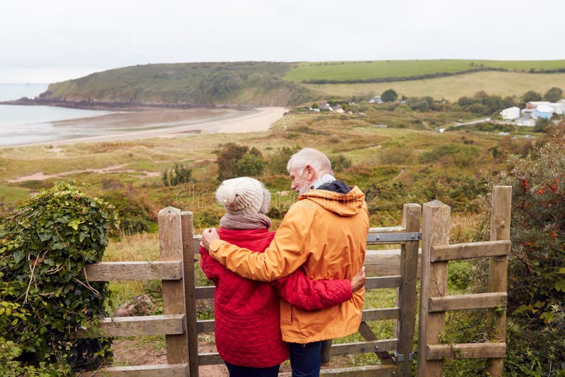 Rear View of Active Senior Couple Looking Out Over Gate As they Walk ...
