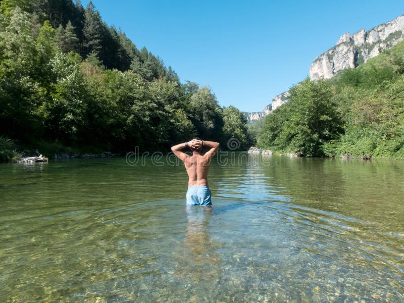 Rear View of a Arms Raised Male Standing into the River while Ba Stock ...