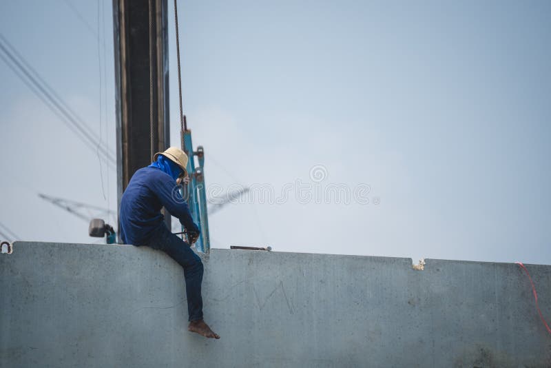 Rear View of an Asian Worker Working on the Edge of a Building at the ...