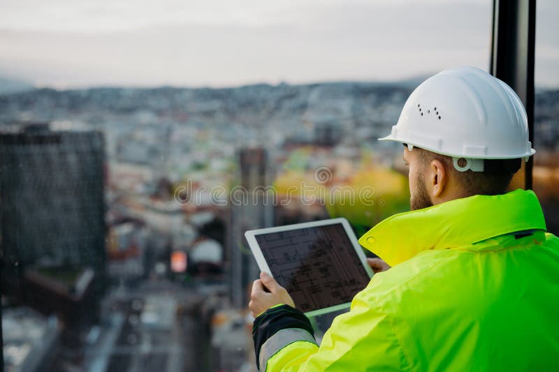 Rear View of Construction Site Manager Using Digital Tablet To Inspect ...