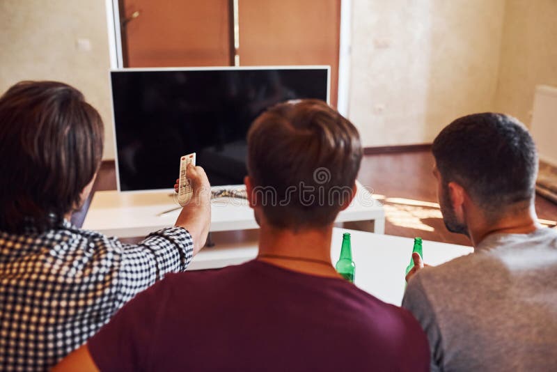 Rear View of Friends Watching TV and Holds Remote Controller in Hand ...