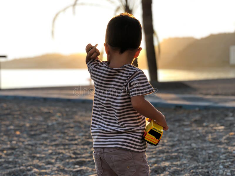 Rear View of a Little Boy on the Beach with a Toy Ambulance in His Hand ...