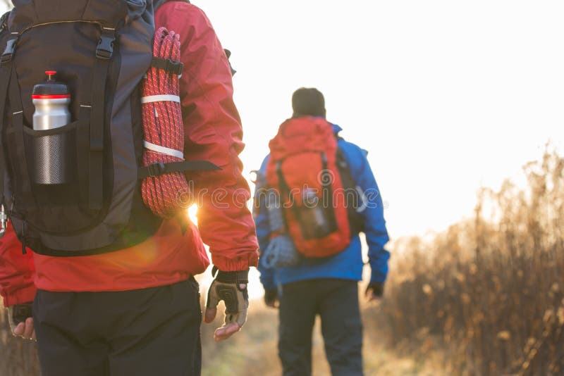 Rear View of Male Backpackers Walking in Field Stock Photo - Image of ...