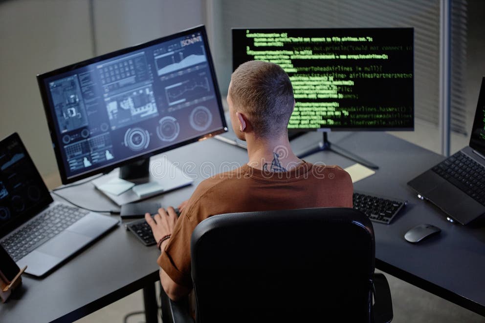 Back of Male Computer Programmer Working at Desk Looking at Screens ...
