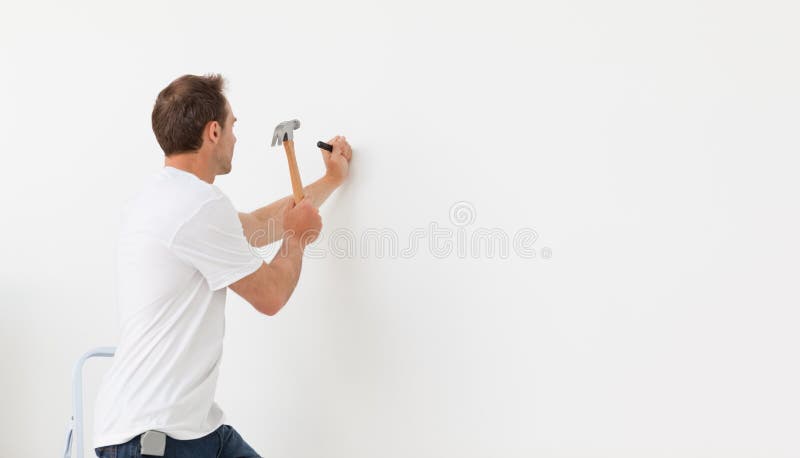 Rear View of a Man Hammering Against a White Wall Stock Image - Image ...
