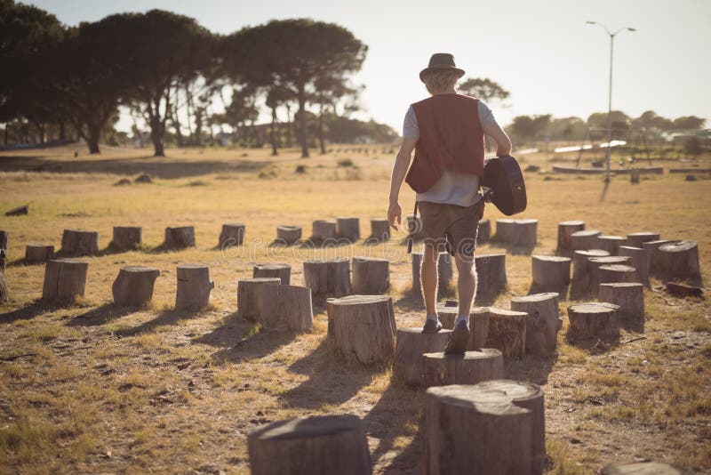 Rear View of Man Holding Guitar while Walking on Tree Stumps Stock ...