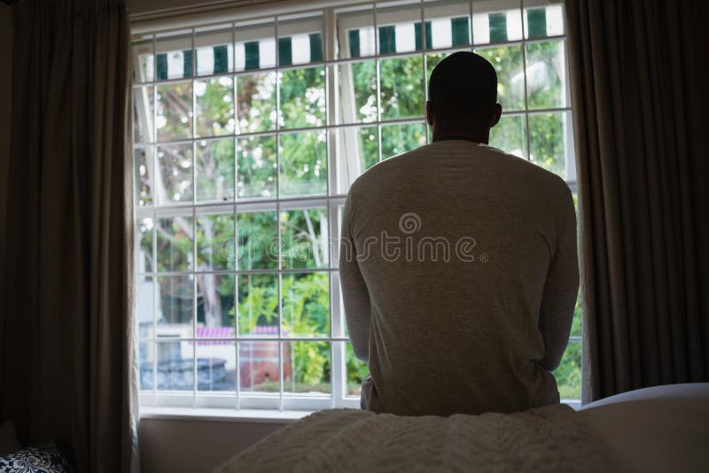 Rear View of Man Sitting on Bed Against Window Stock Image - Image of ...